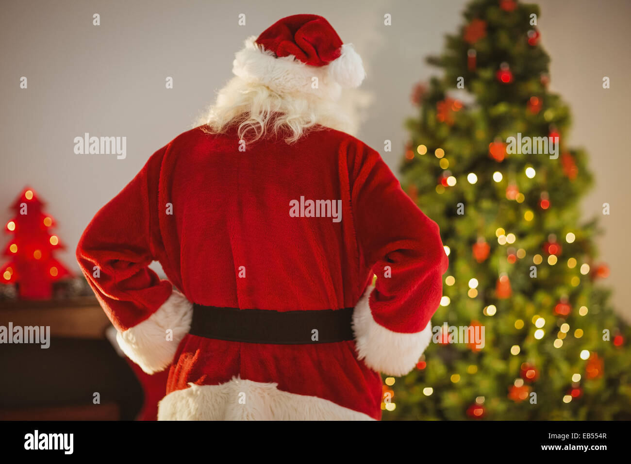 Rear view of santa standing in front of the christmas tree Stock Photo ...