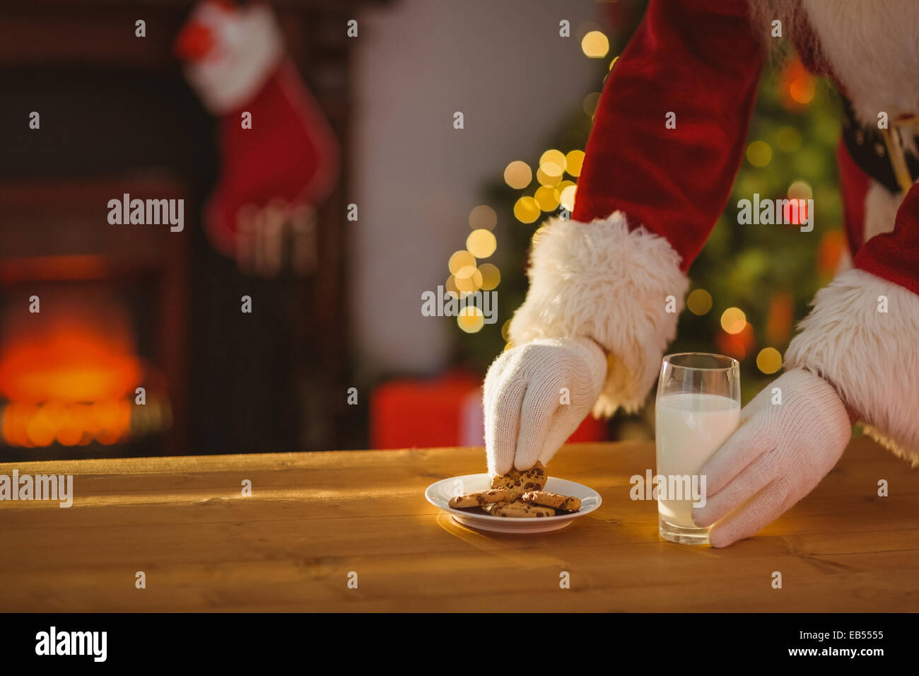 Santa claus picking cookie and glass of milk Stock Photo - Alamy