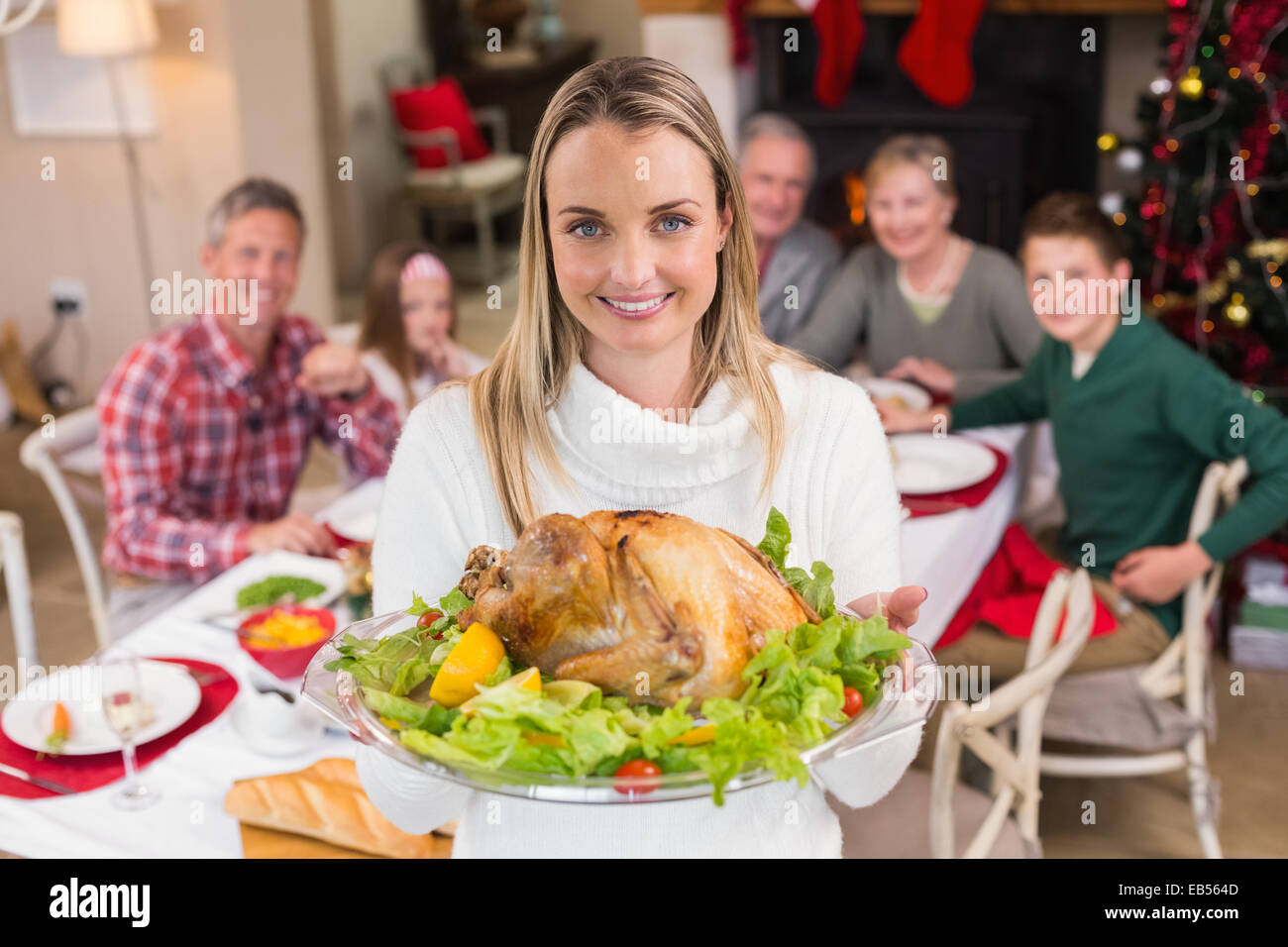 Pretty woman showing the roast turkey in front of her family Stock ...