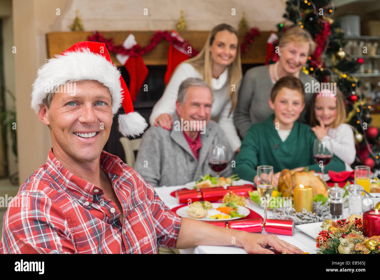 Smiling father in santa hat posing in front of his family Stock Photo ...