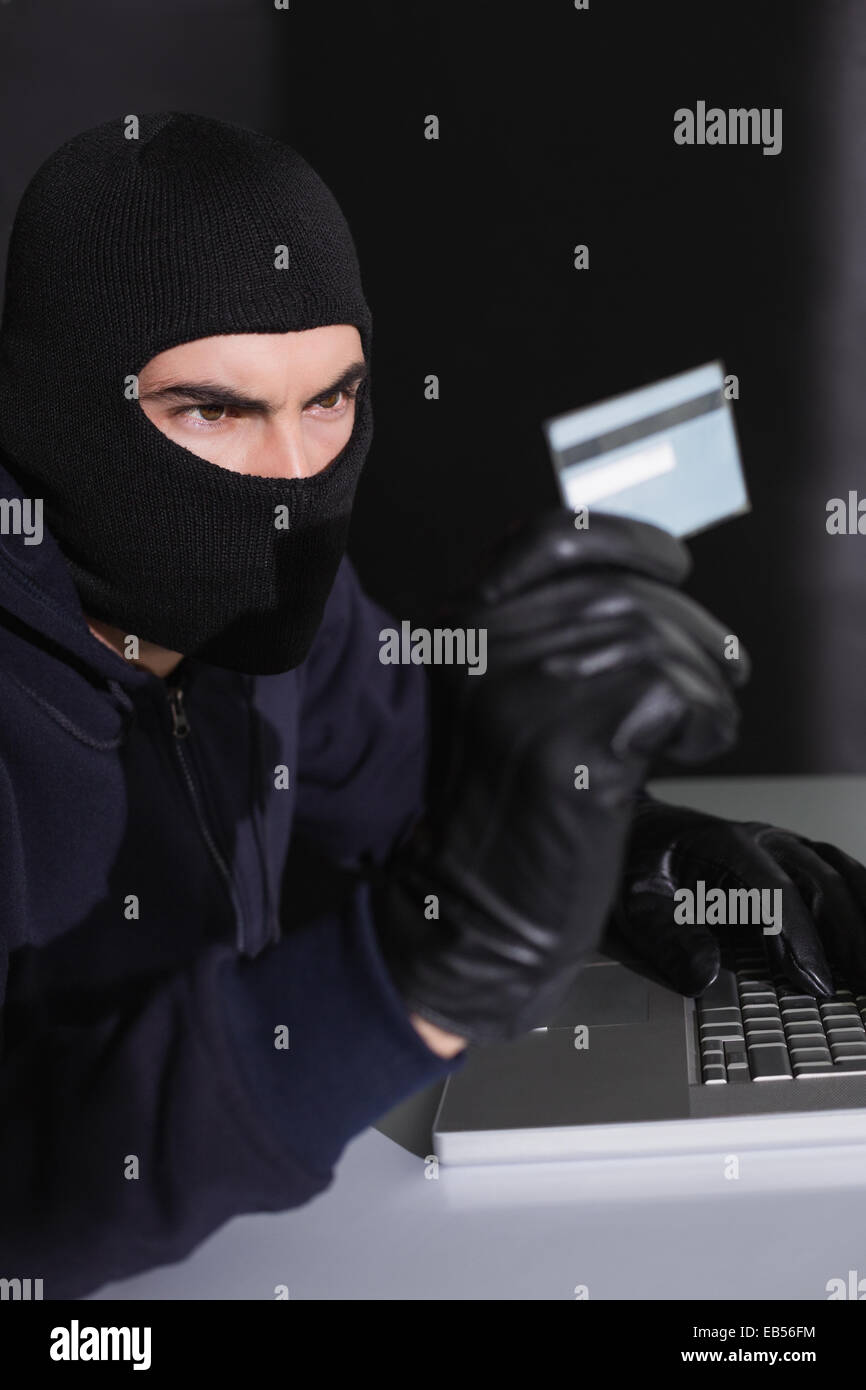 Hacker in balaclava spending money online Stock Photo - Alamy