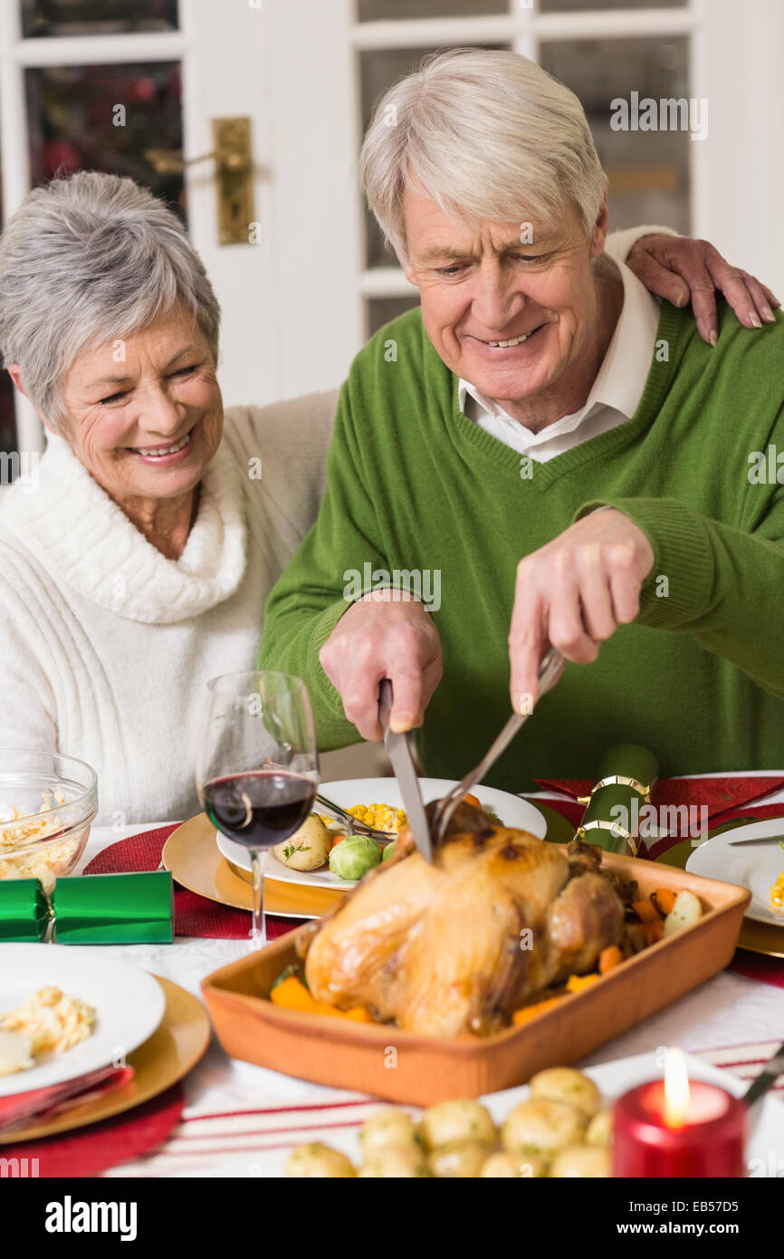 Man carving chicken while his wife having arm around him Stock Photo ...