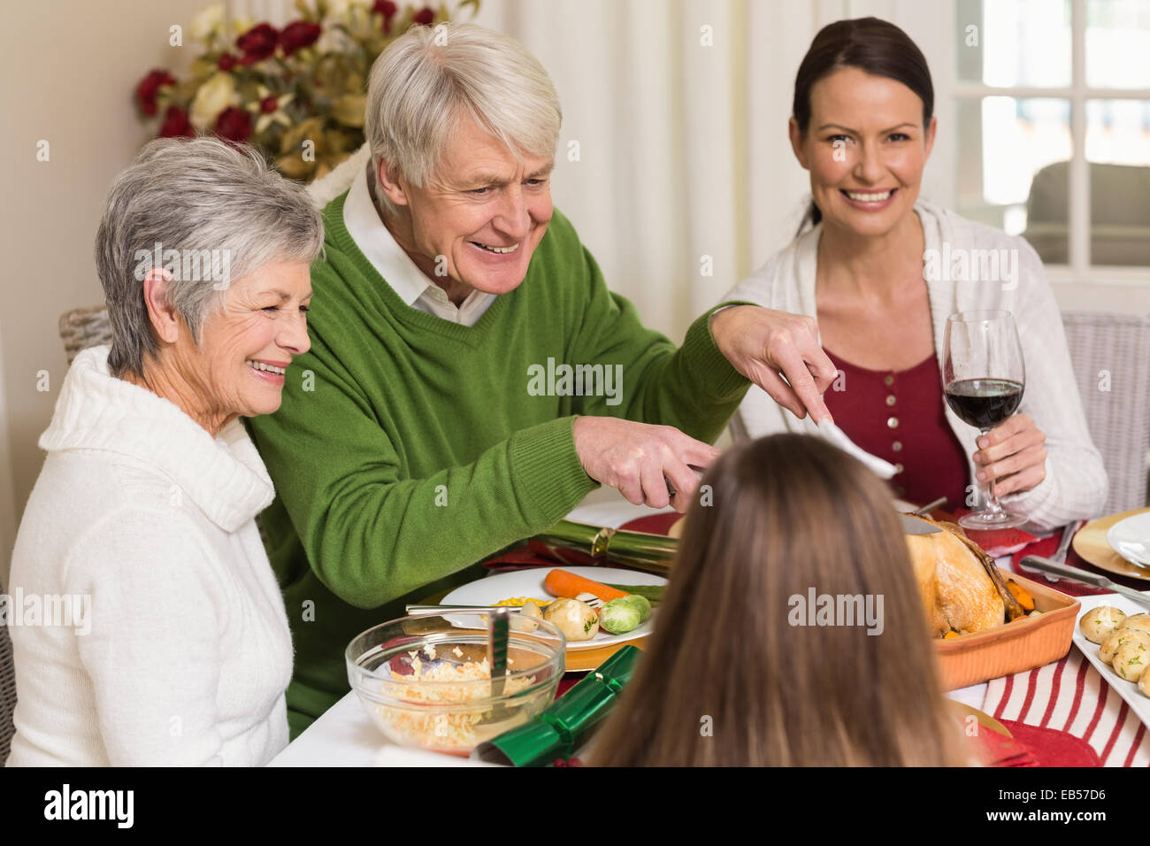 Smiling grandfather carving chicken during christmas dinner Stock Photo ...