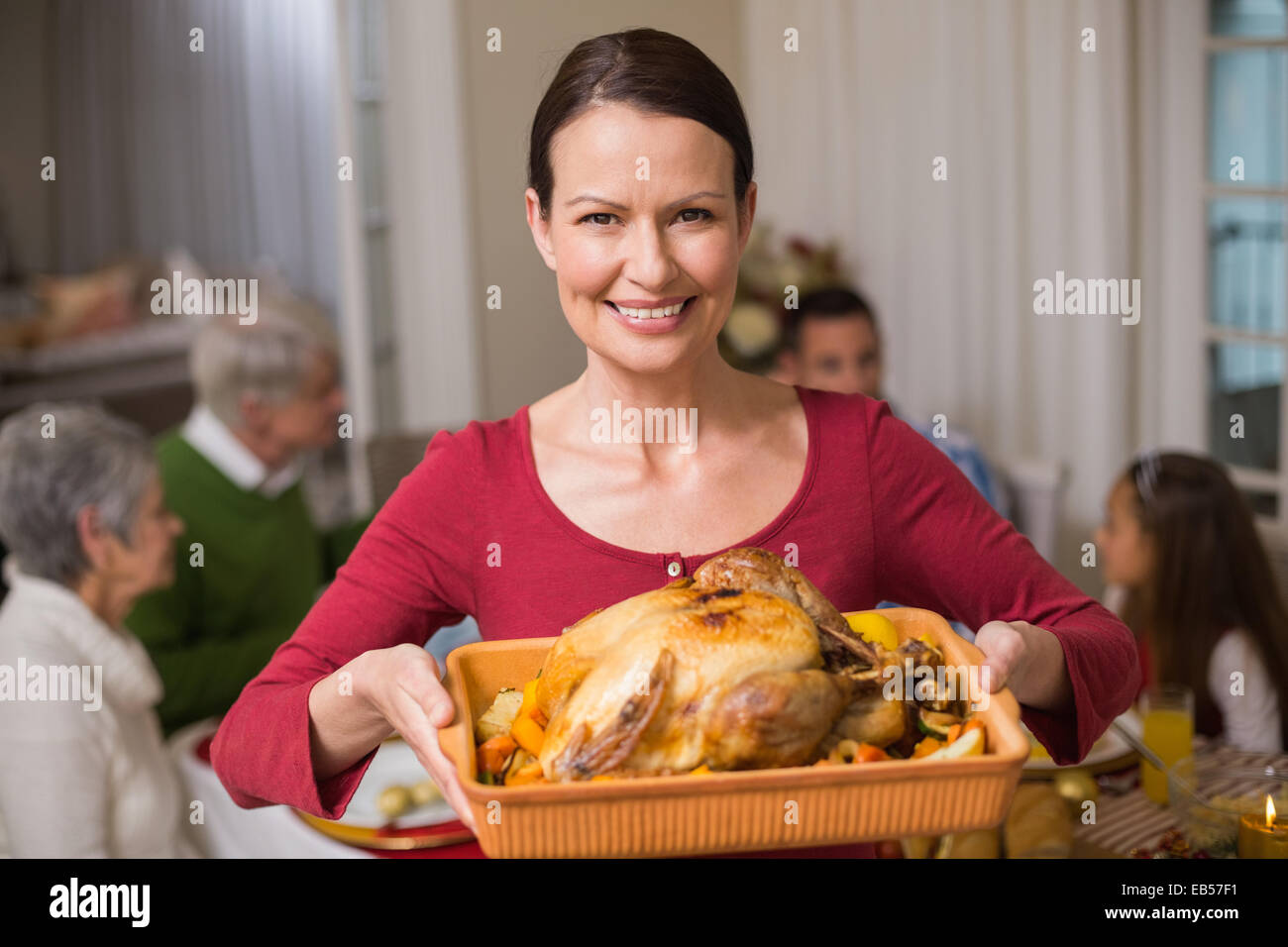Pretty woman showing the roast turkey in front of her family Stock ...