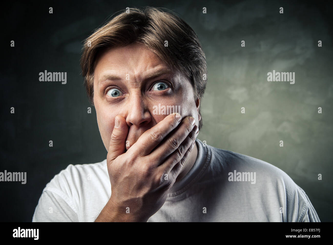handsome man scared over dark gray background Stock Photo - Alamy