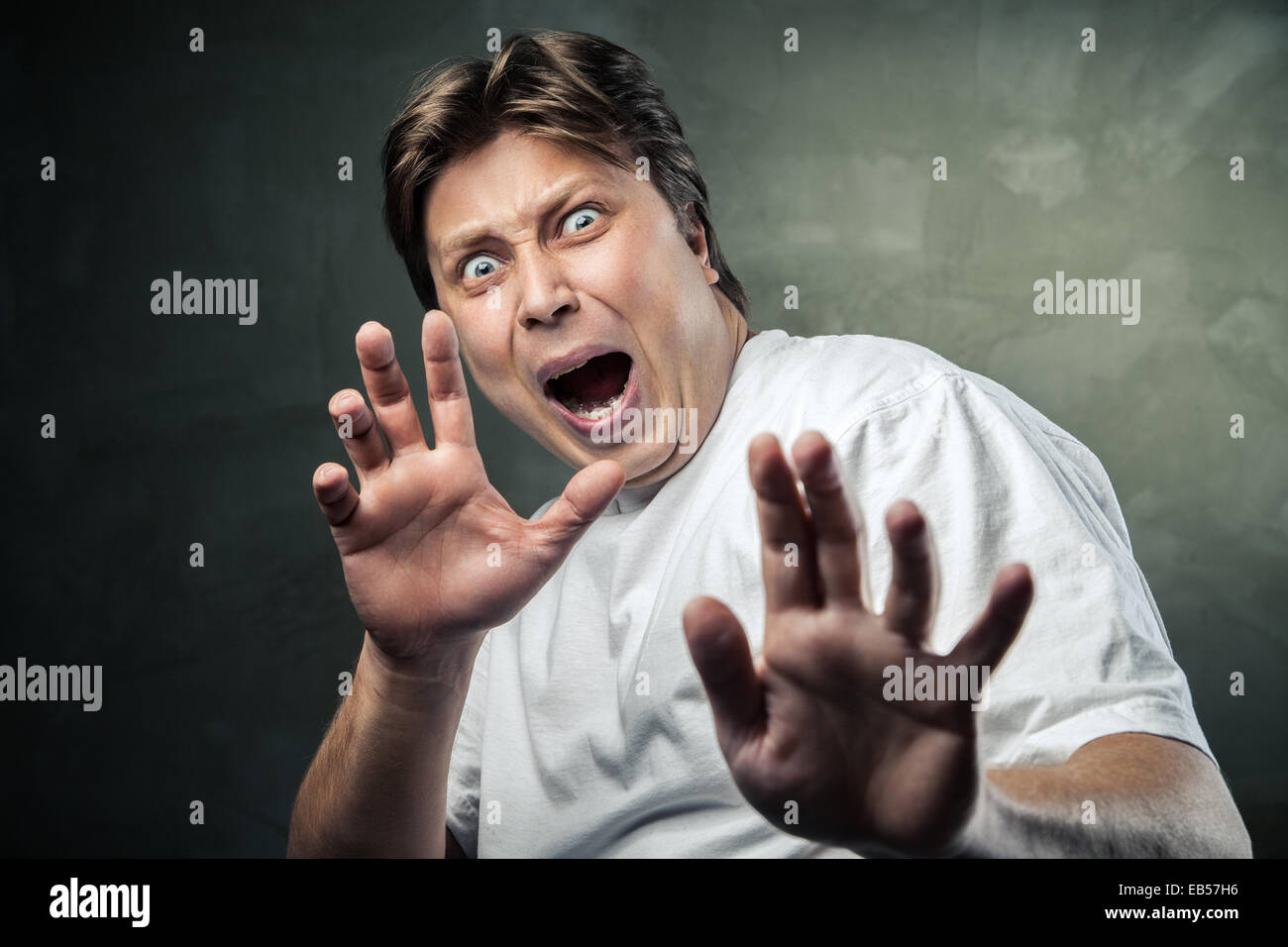 handsome man scared over dark gray background Stock Photo - Alamy