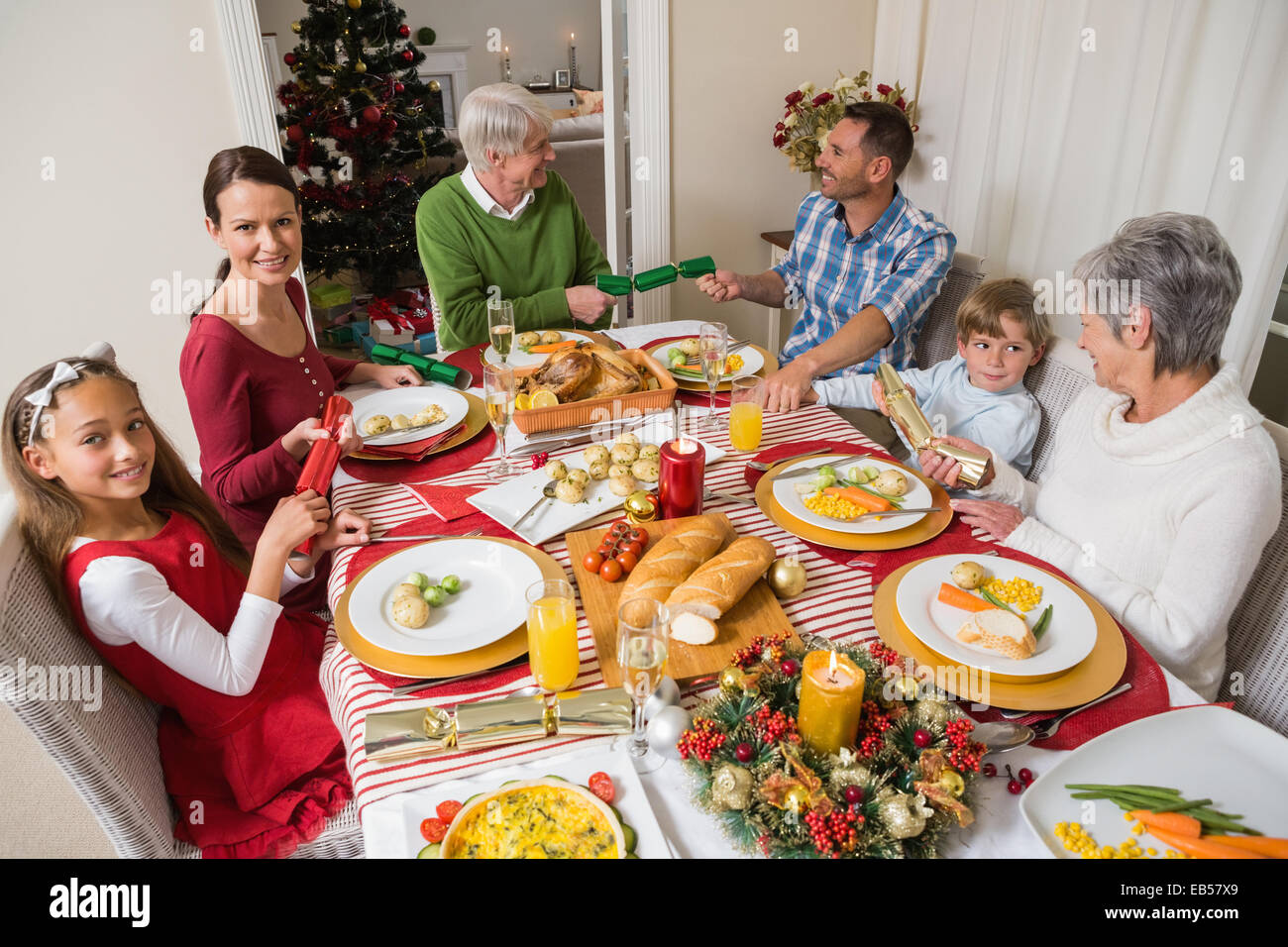 Smiling family pulling christmas crackers at the dinner table Stock ...