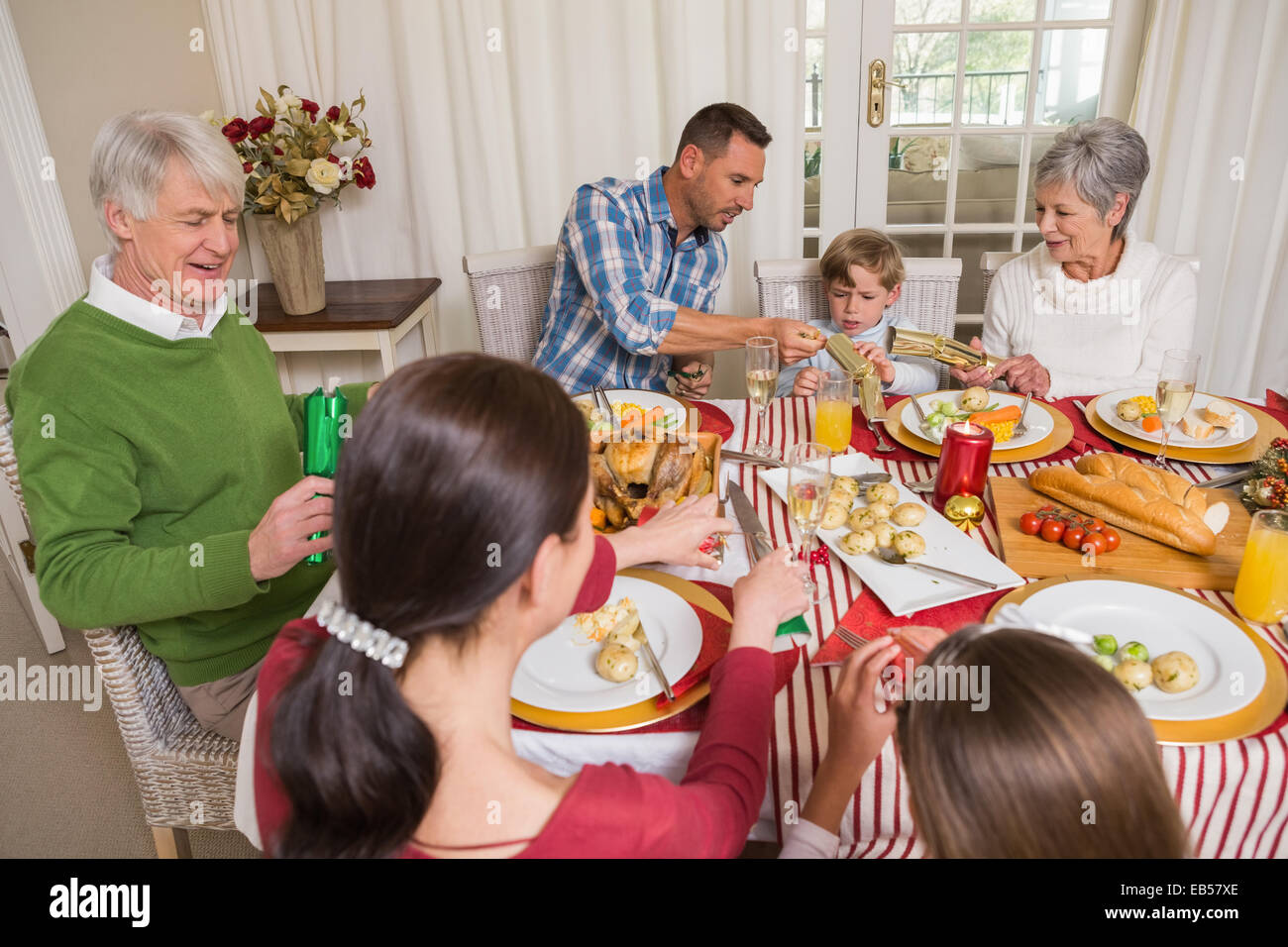 Smiling family pulling christmas crackers at the dinner table Stock ...