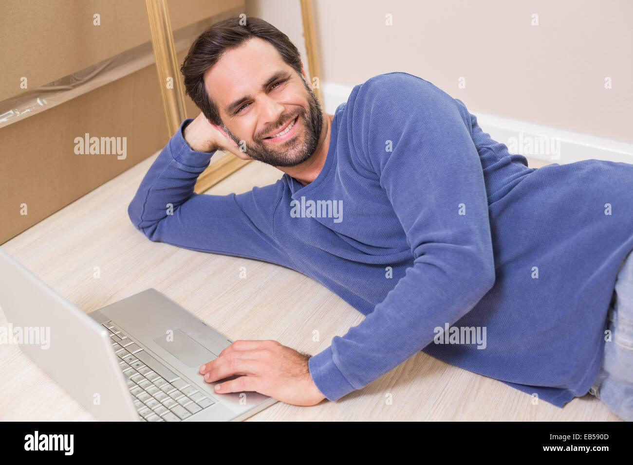 Happy man lying on floor using laptop Stock Photo - Alamy
