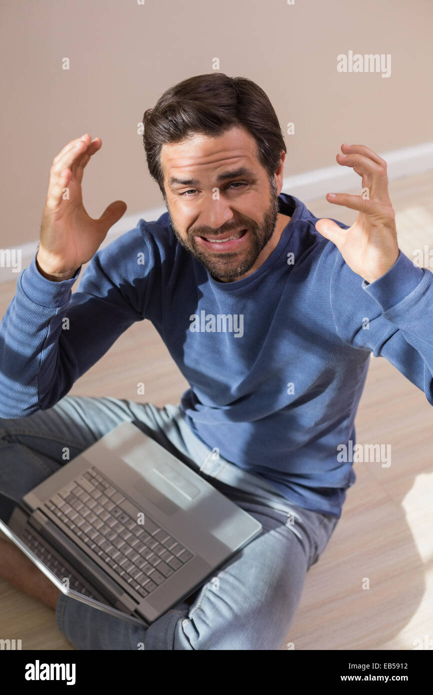 Strssed man sitting on floor using laptop Stock Photo - Alamy