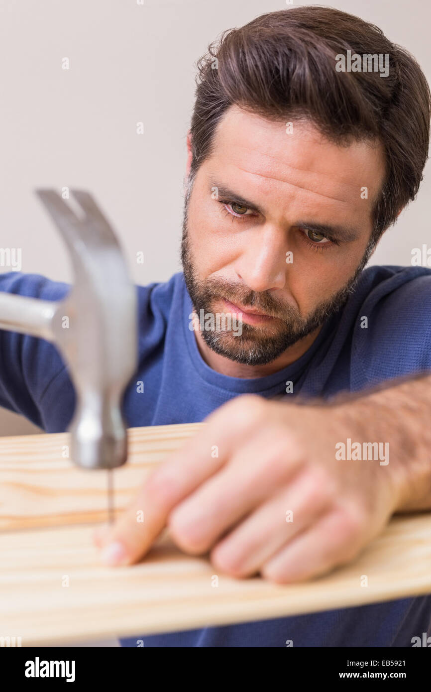Casual man hammering nail in plank Stock Photo - Alamy