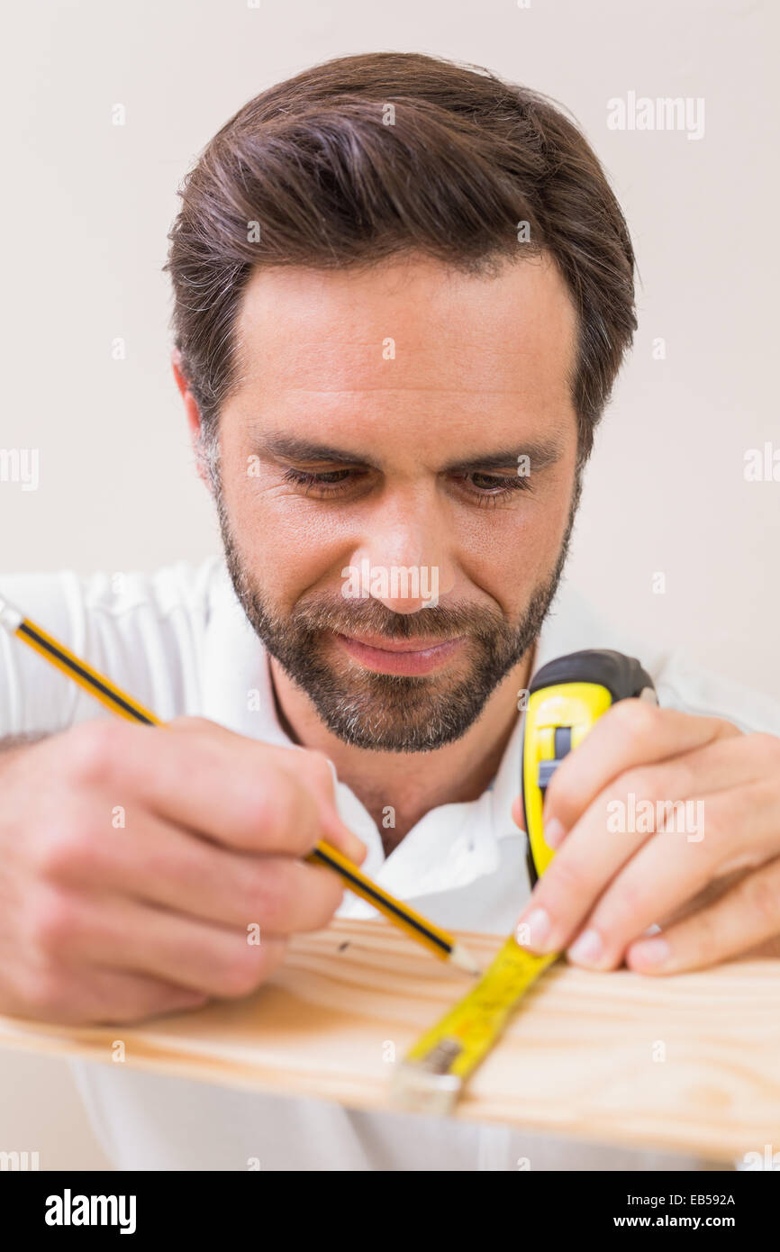 Casual man measuring plank of wood Stock Photo - Alamy