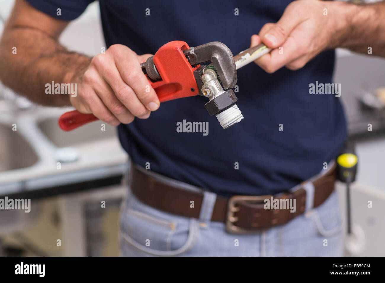Plumber fixing pipe with wrench Stock Photo - Alamy