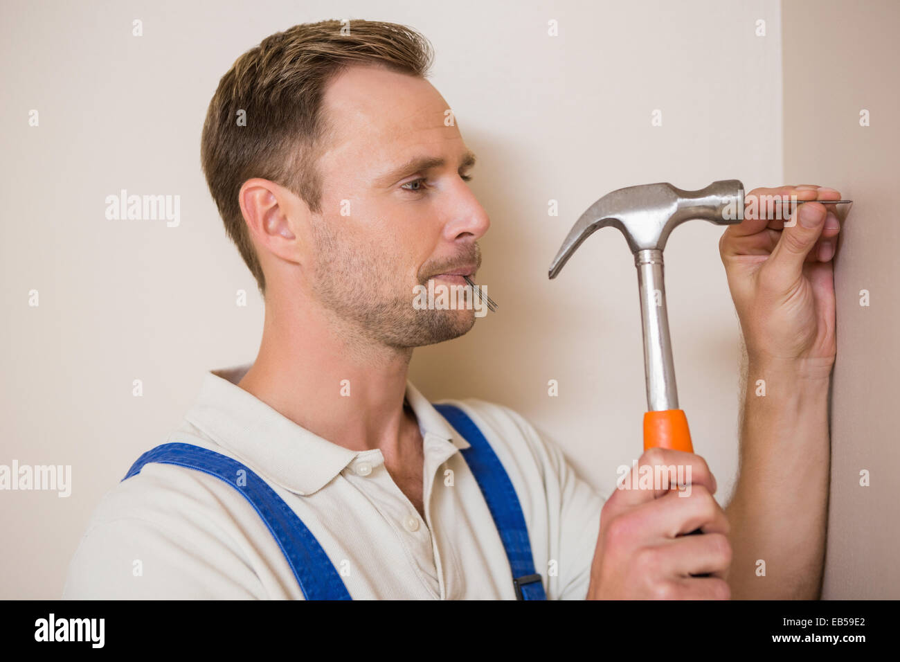 Man hammering nail in the wall Stock Photo - Alamy