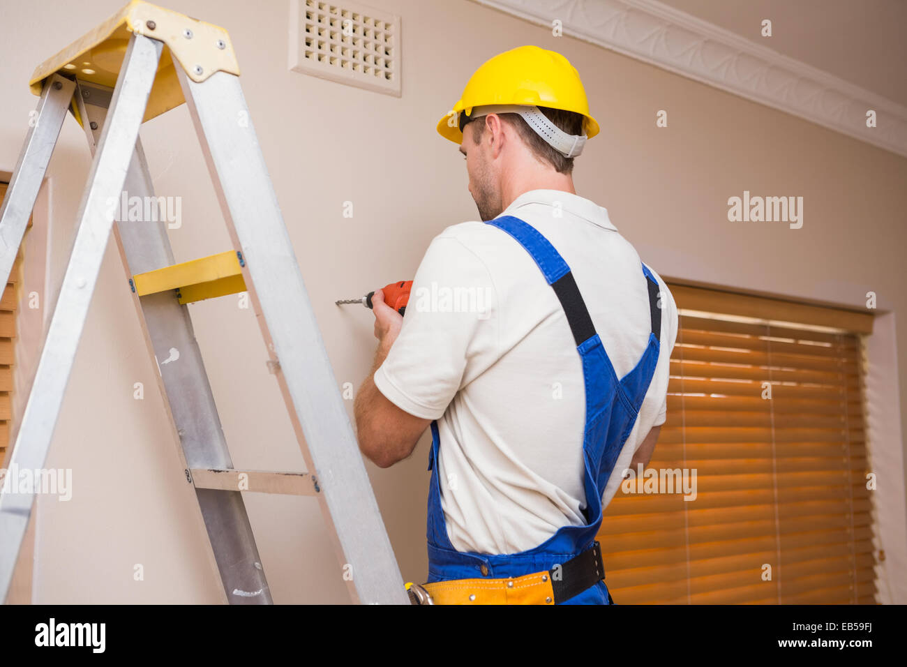 Construction worker drilling hole in wall Stock Photo - Alamy