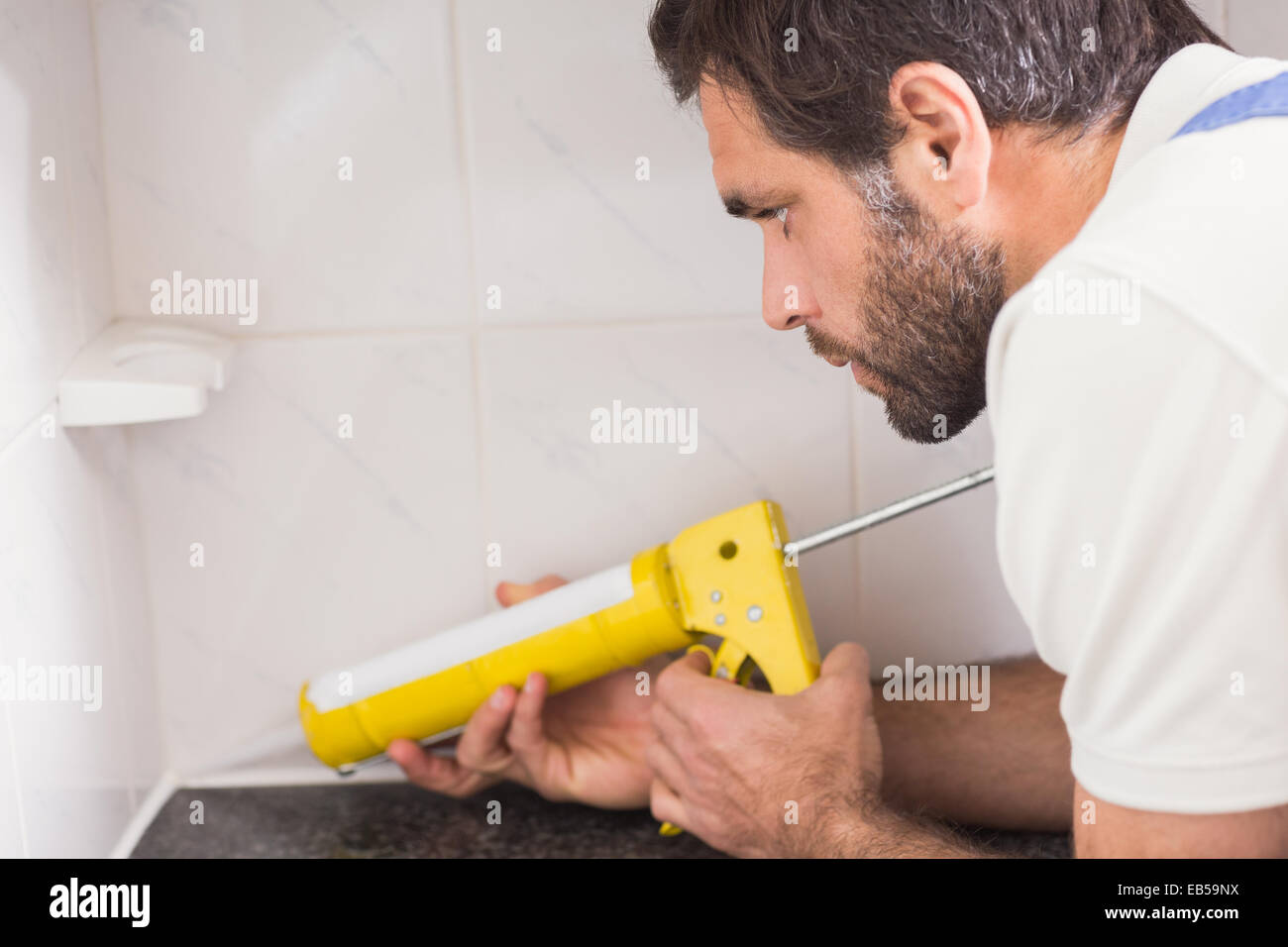 Plumber putting filling in between tiles Stock Photo - Alamy