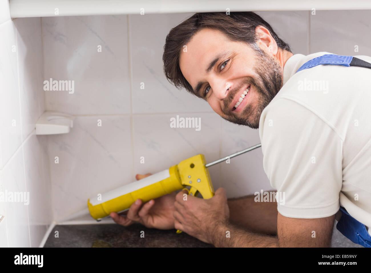 Plumber putting filling in between tiles Stock Photo - Alamy
