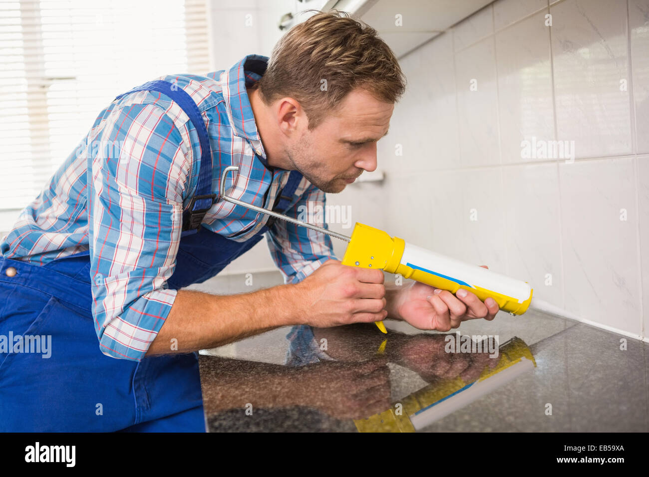 Plumber putting filling in between tiles Stock Photo - Alamy