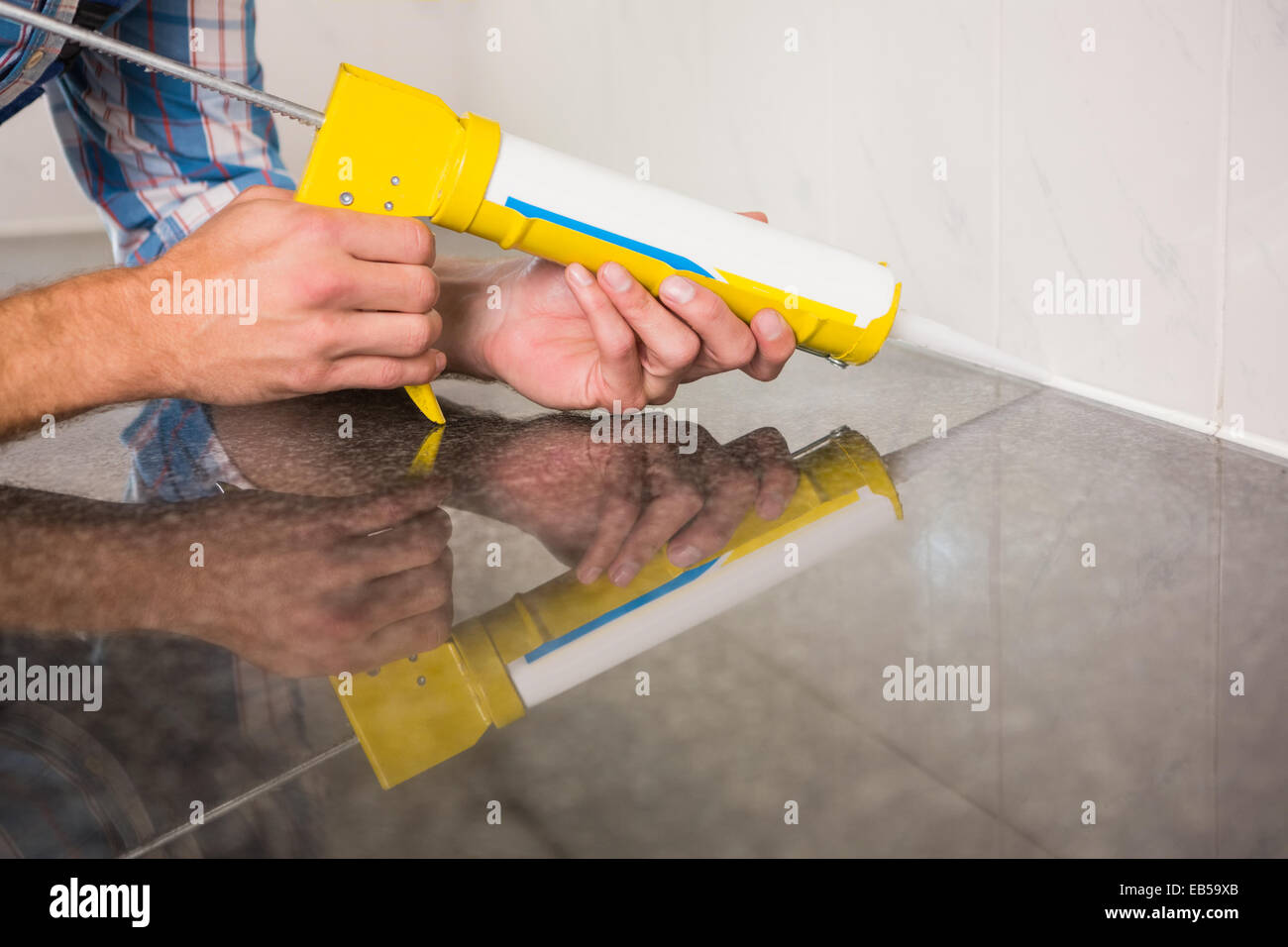 Plumber putting filling in between tiles Stock Photo - Alamy