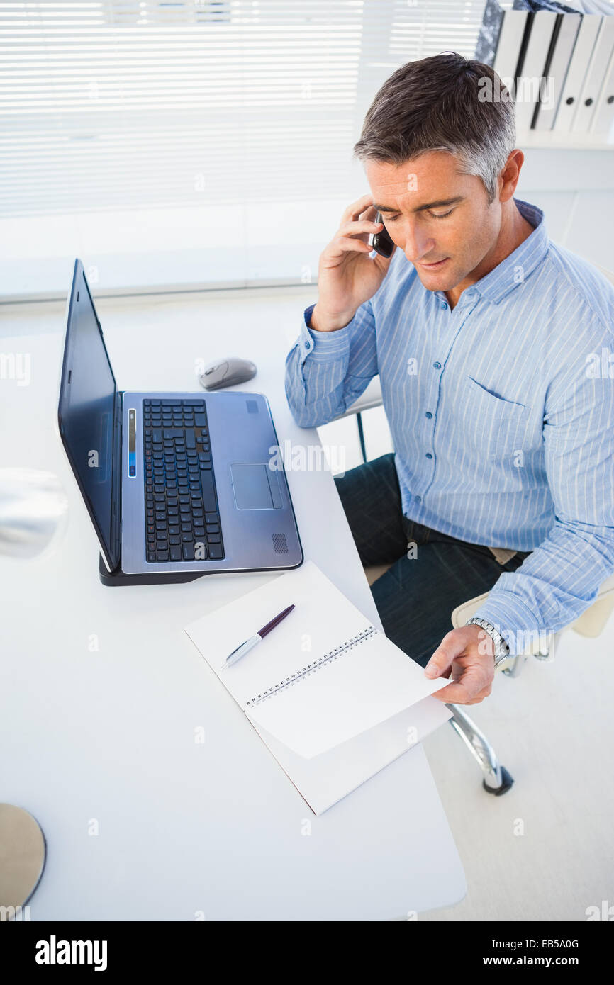 Man on the phone and looking in notebook Stock Photo - Alamy