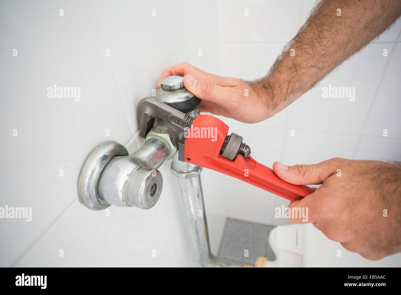 Plumber fixing tap with wrench Stock Photo - Alamy