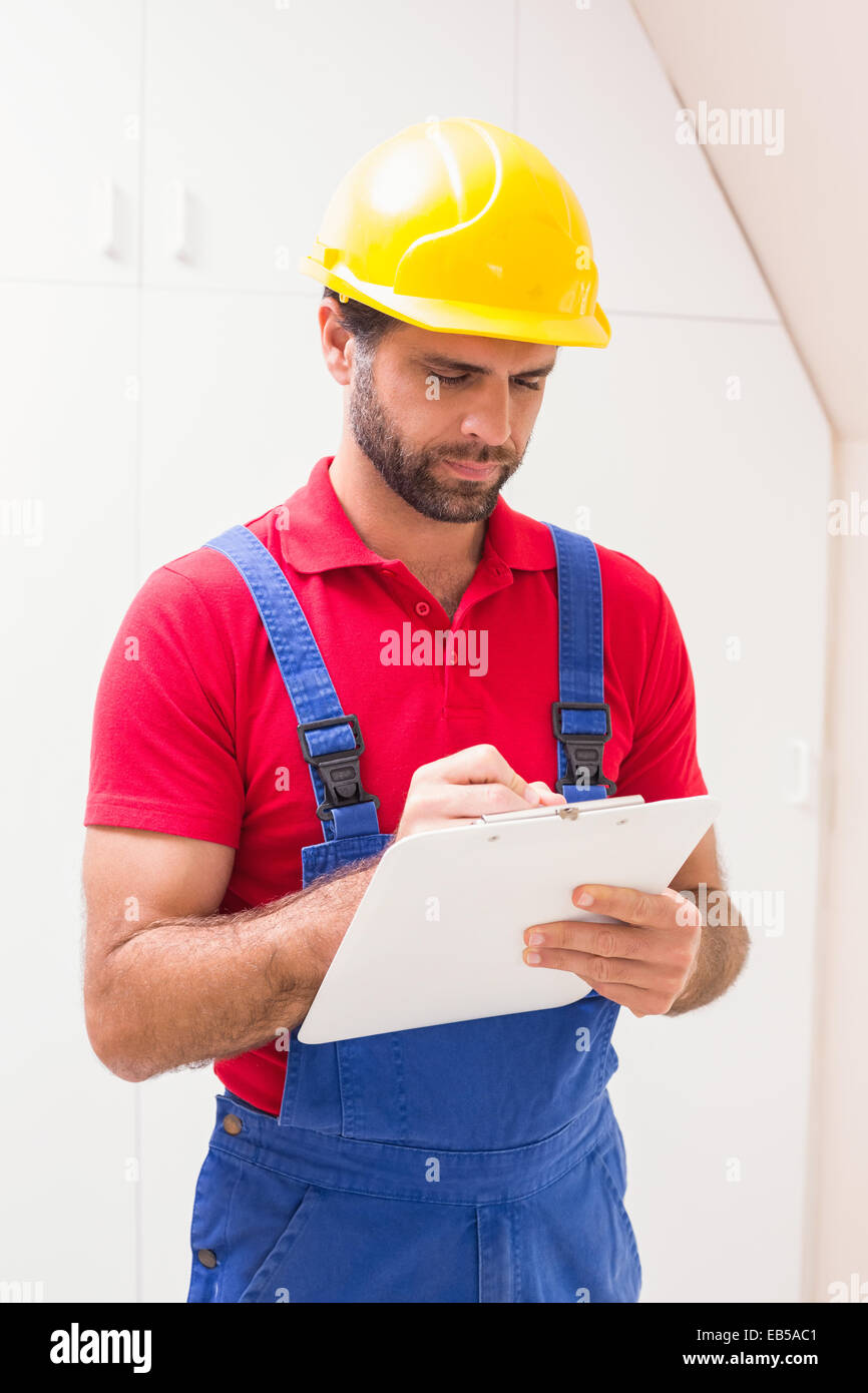 Construction worker taking notes on clipboard Stock Photo - Alamy