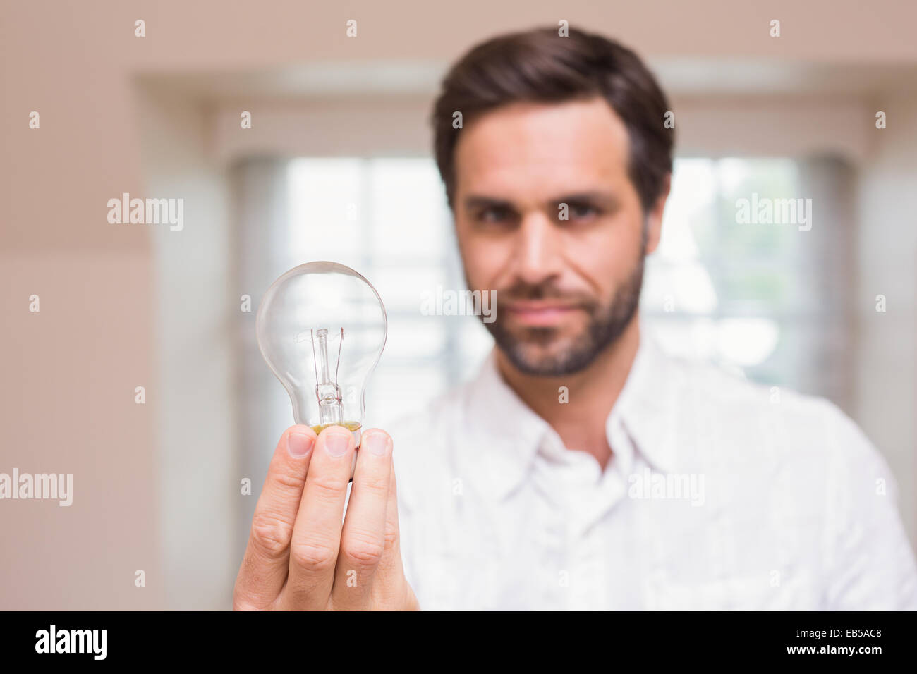 Man showing light bulb to camera Stock Photo - Alamy