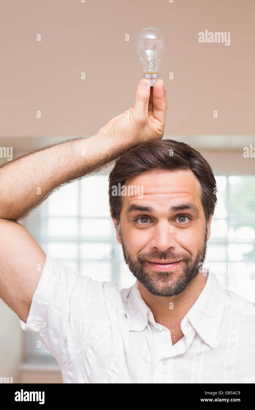 Man holding light bulb over his head Stock Photo - Alamy