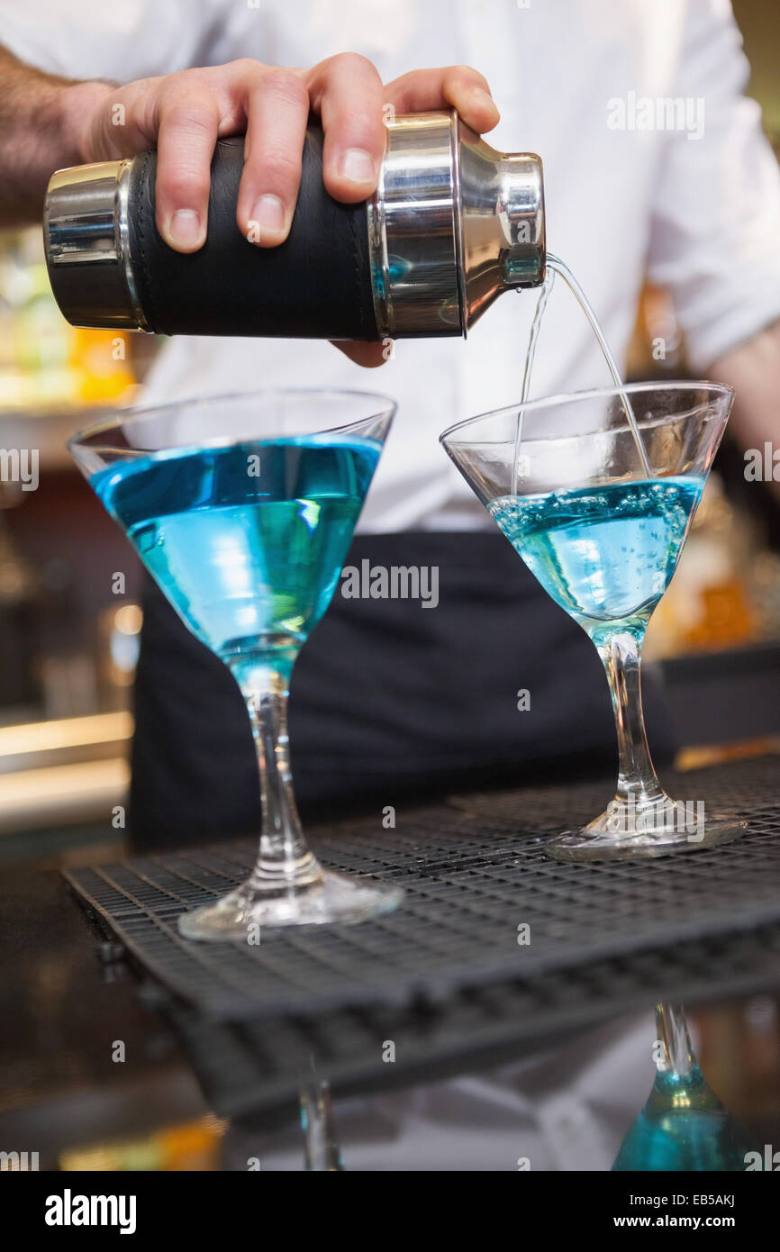 Bartender pouring cocktail into glasses Stock Photo - Alamy