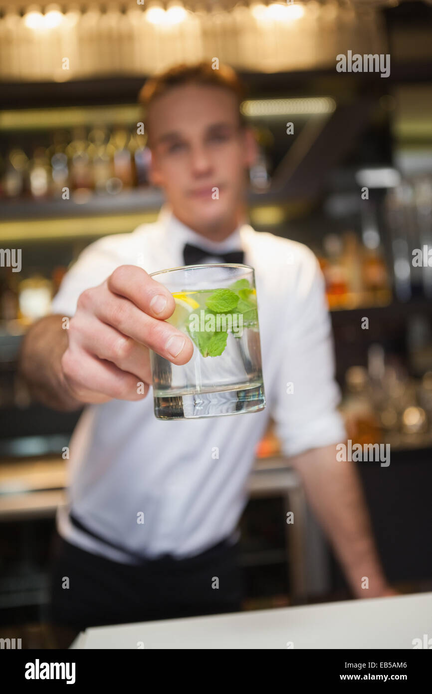 Happy bartender offering cocktail to camera Stock Photo - Alamy