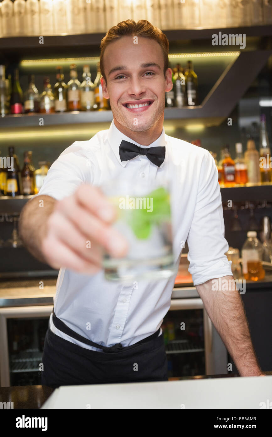 Happy bartender offering cocktail to camera Stock Photo - Alamy