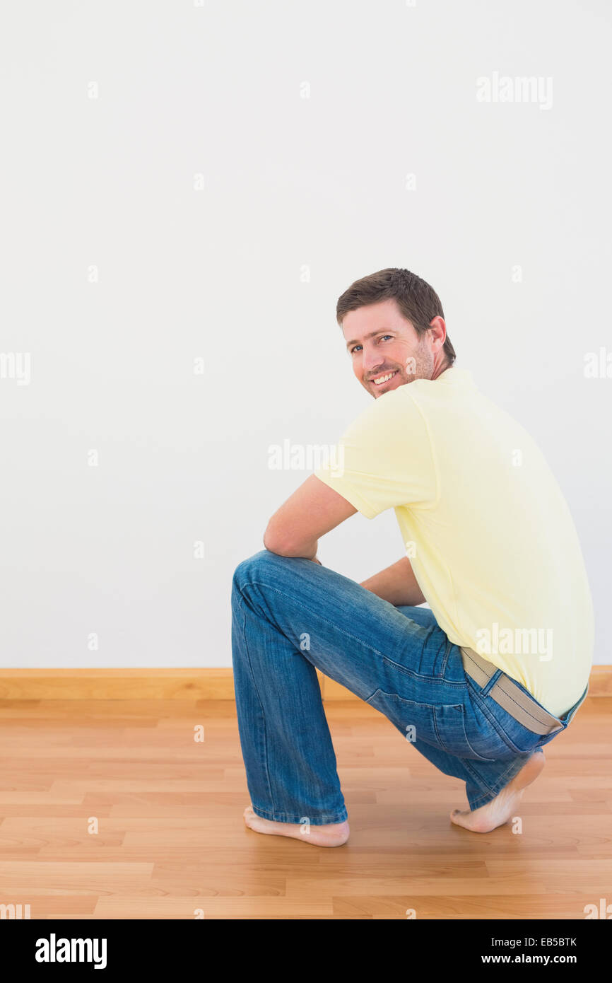 Casual man crouching on floor looking at wall at home Stock Photo - Alamy