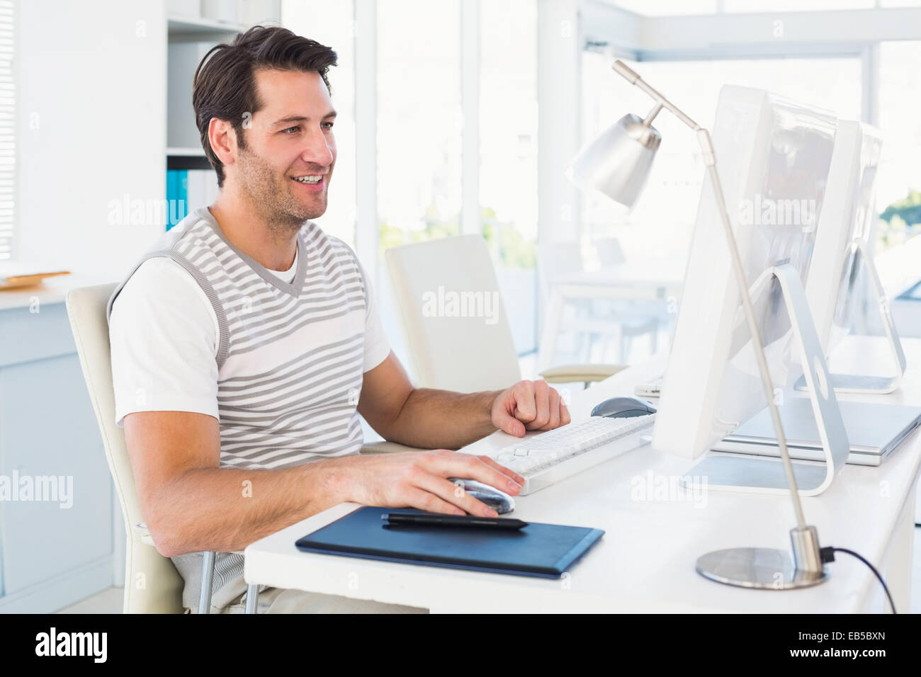 Smiling casual young man using computer Stock Photo - Alamy