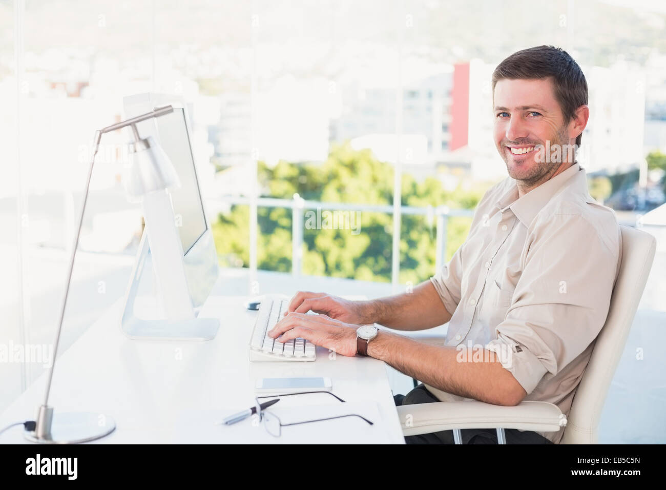 Smiling businessman using his computer at his desk Stock Photo - Alamy