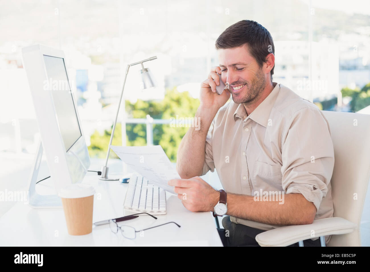 Smiling businessman making a call and reading a document Stock Photo ...