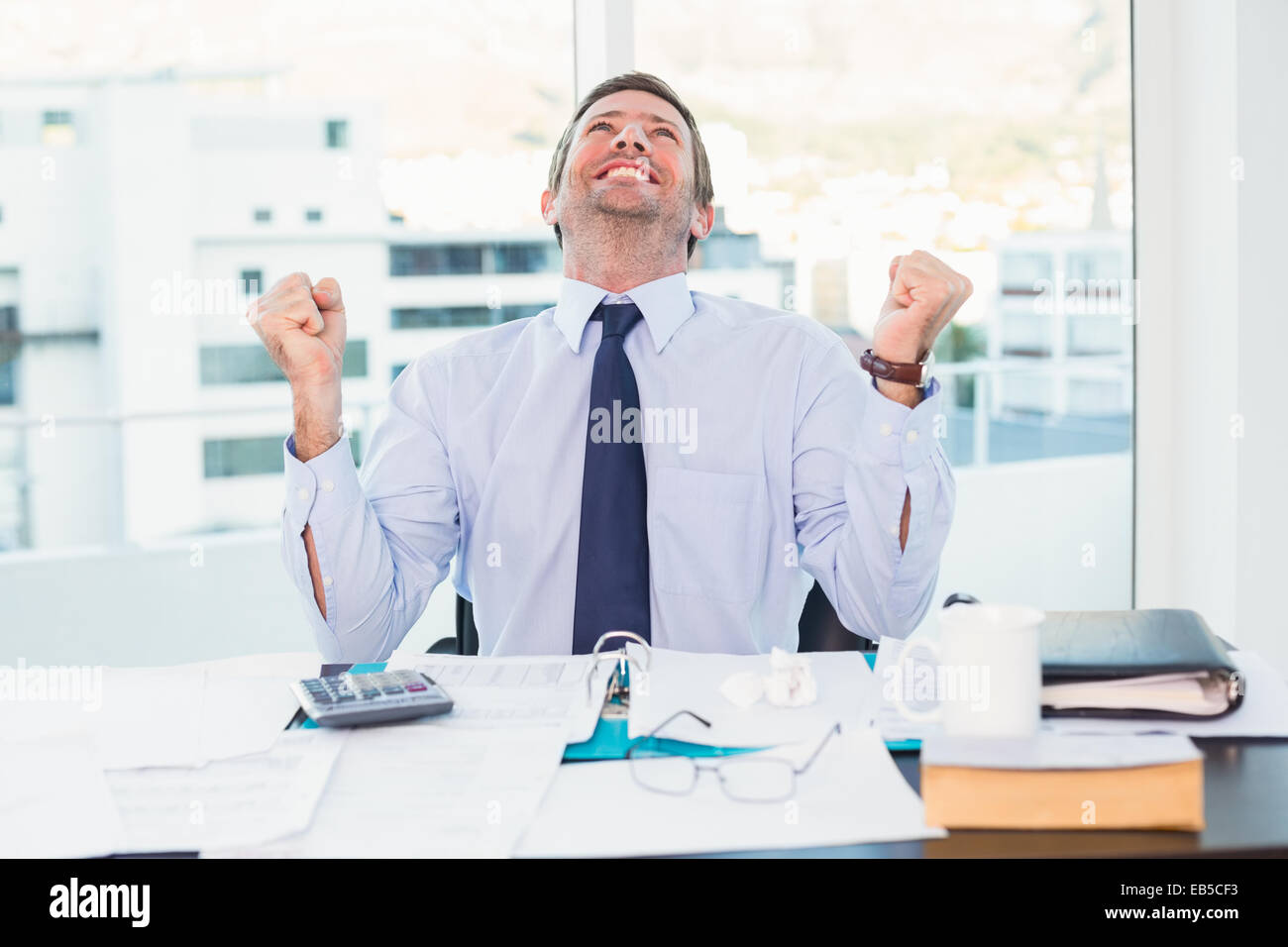 Cheering businessman at his desk Stock Photo - Alamy