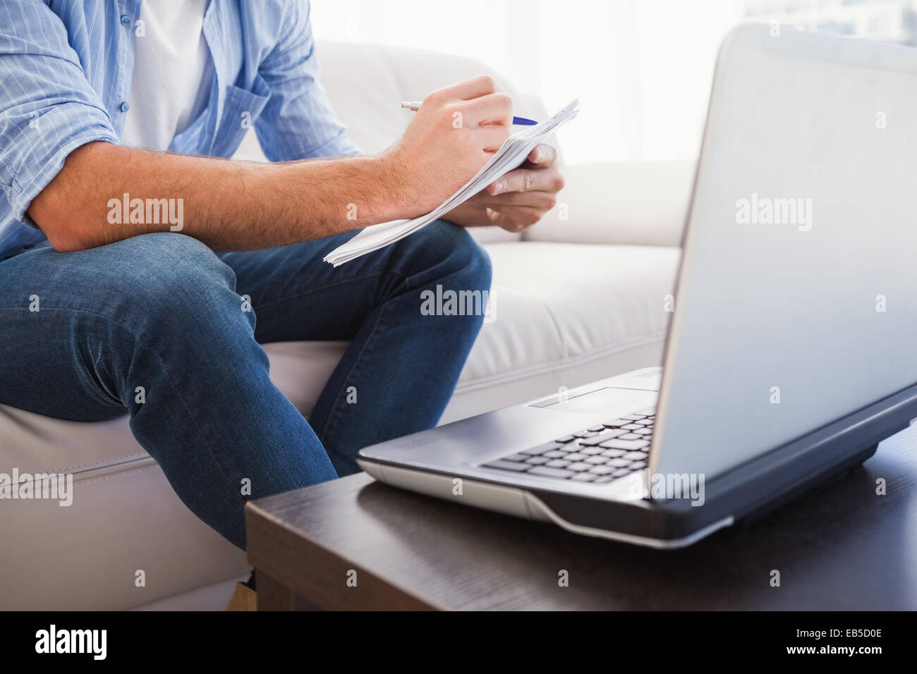 Man using laptop and taking notes Stock Photo - Alamy