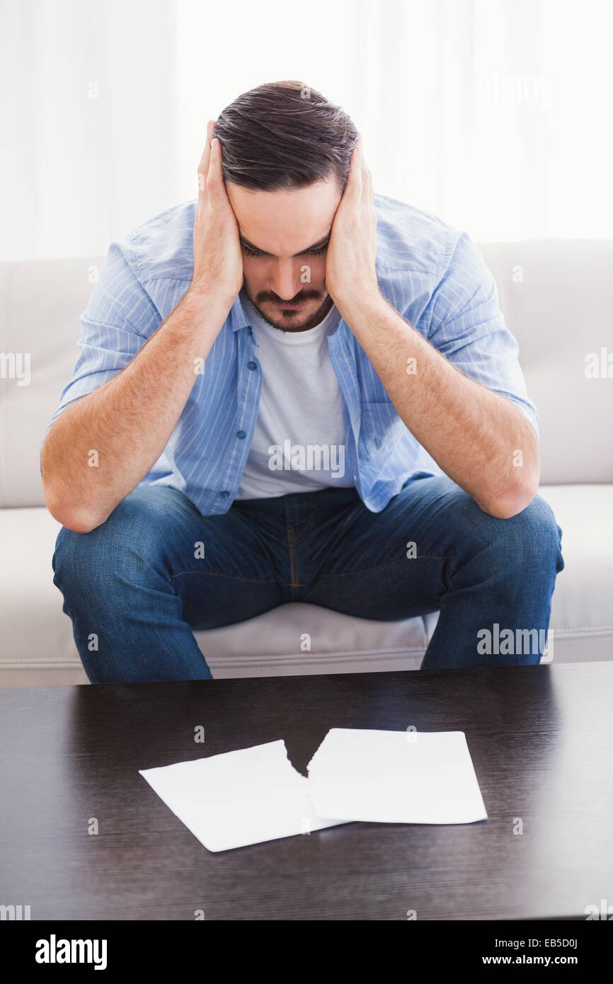 Upset man sitting head in hands on couch Stock Photo - Alamy