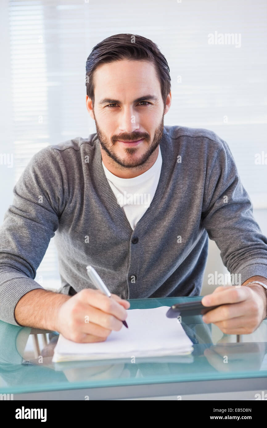 Happy casual man writing on sheets paying bills Stock Photo - Alamy