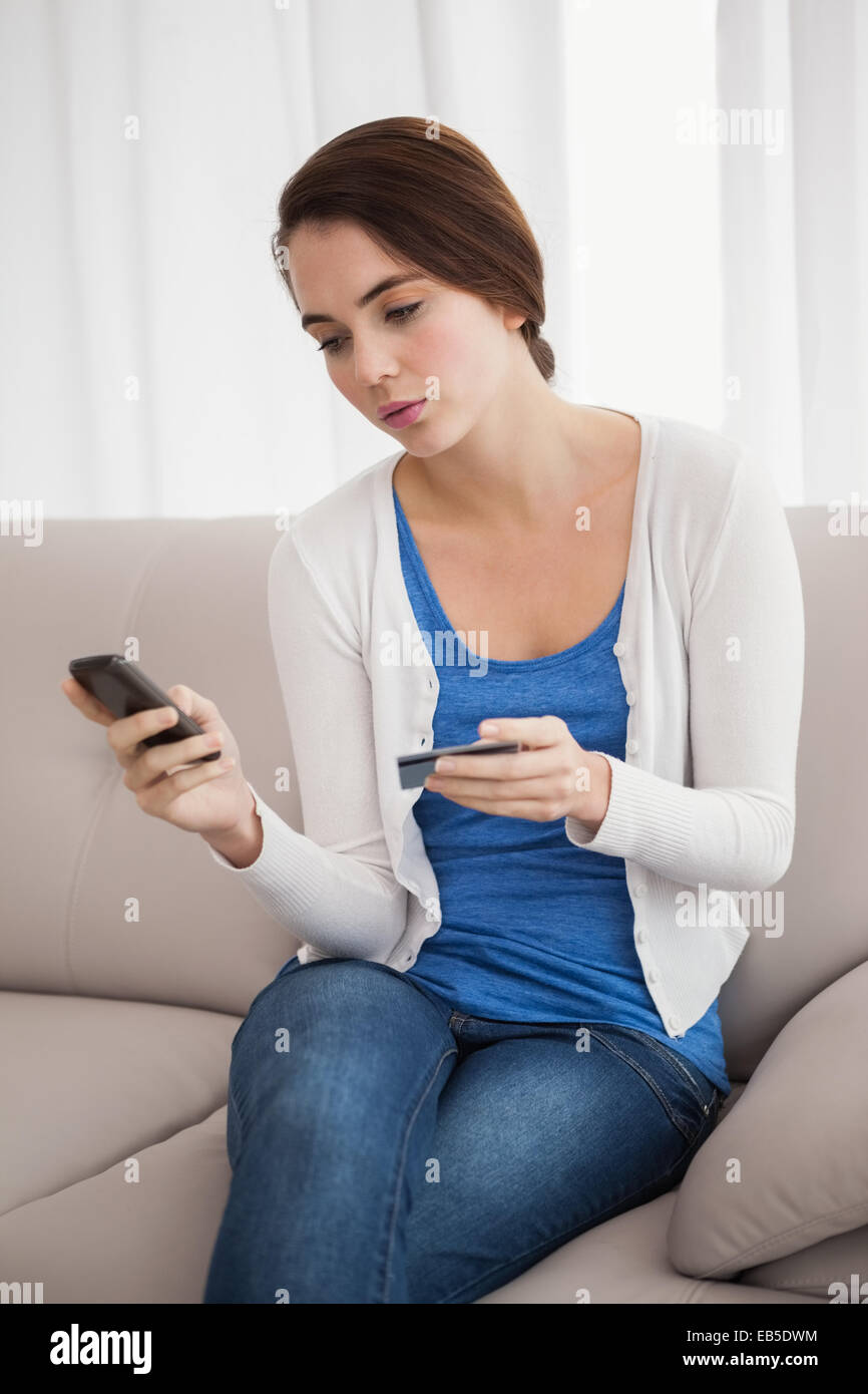 Pretty brunette paying over the phone Stock Photo - Alamy