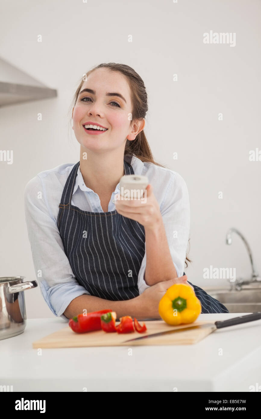 Pretty brunette cooking and watching tv Stock Photo - Alamy