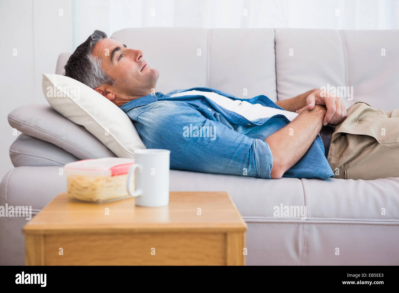 Relaxed man lying on the couch Stock Photo - Alamy