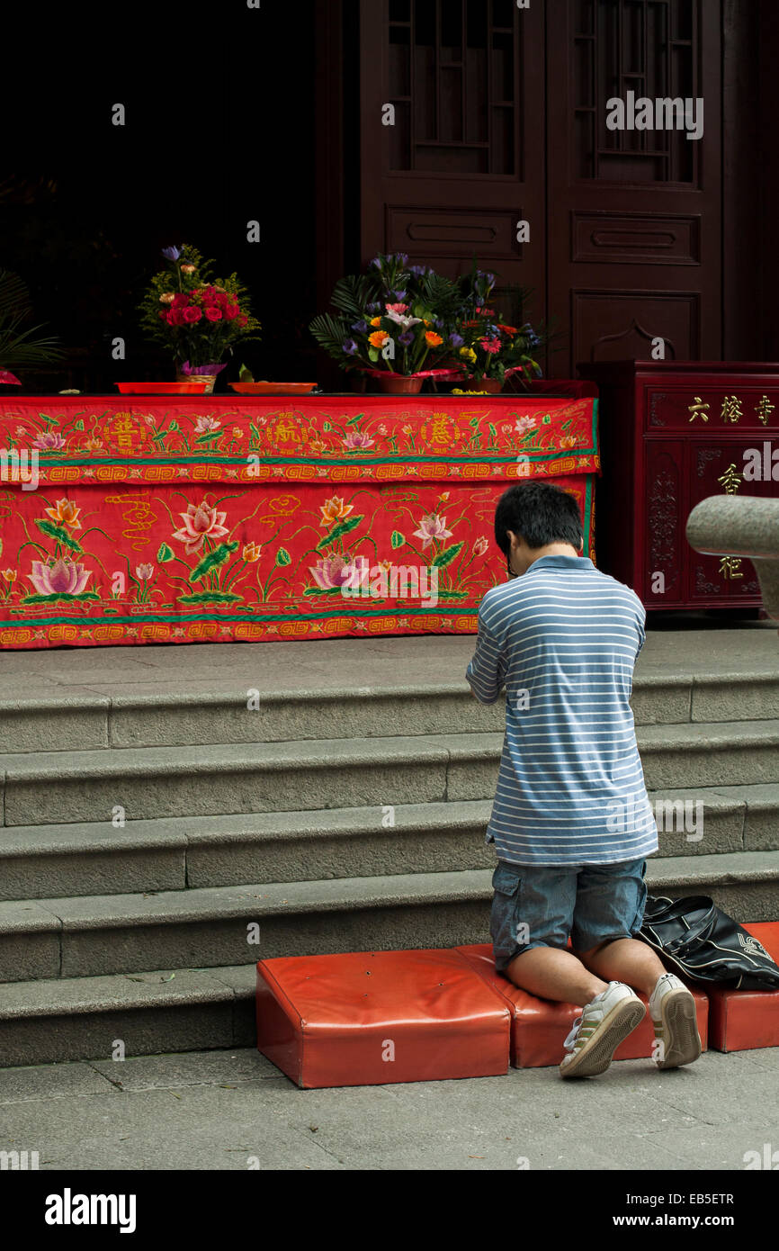 one person kneeling and standing in front of prayer shrine, South East ...