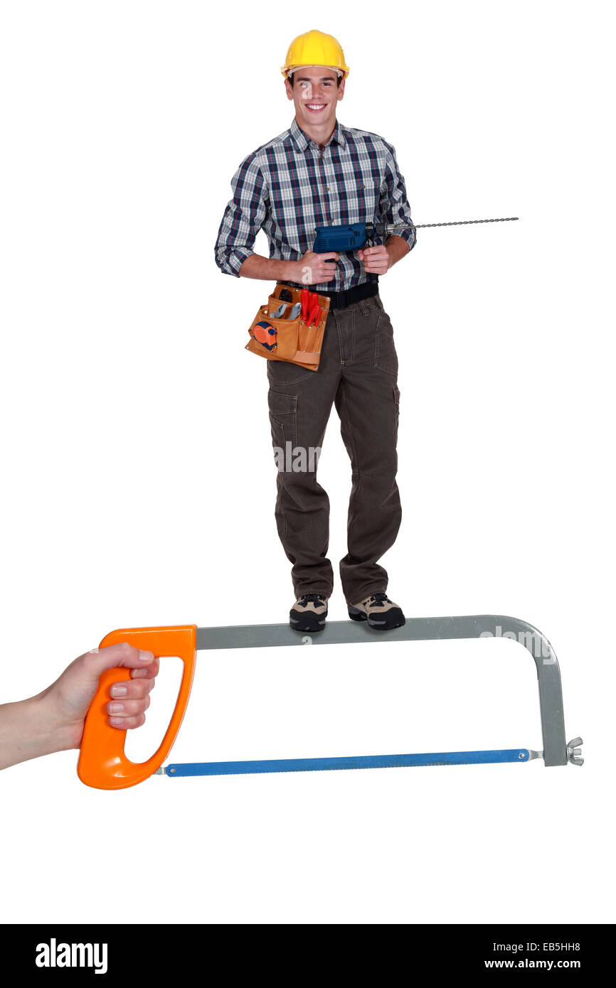 Handyman with drill standing on giant hacksaw Stock Photo - Alamy