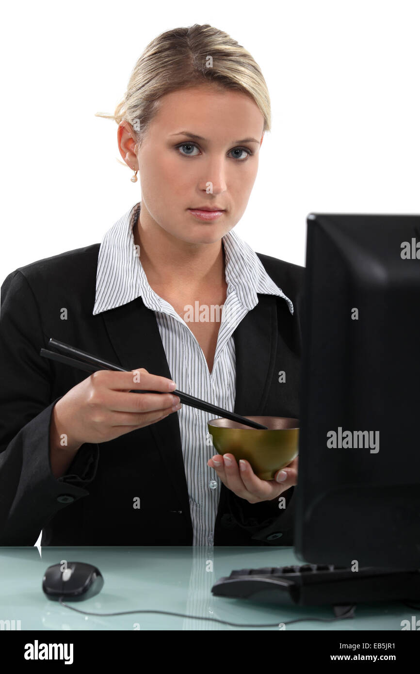 Woman eating at her desk Stock Photo - Alamy