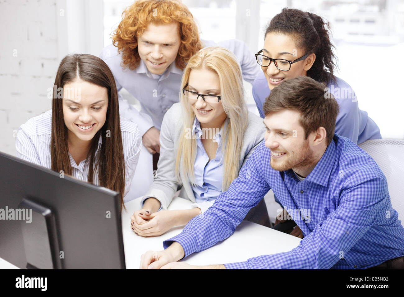 smiling business team looking at computer monitor Stock Photo - Alamy