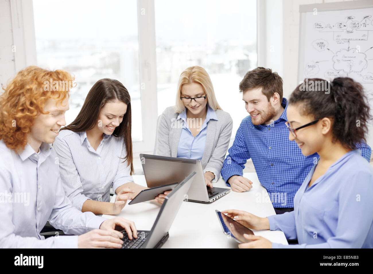 smiling team with laptop and table pc computers Stock Photo - Alamy