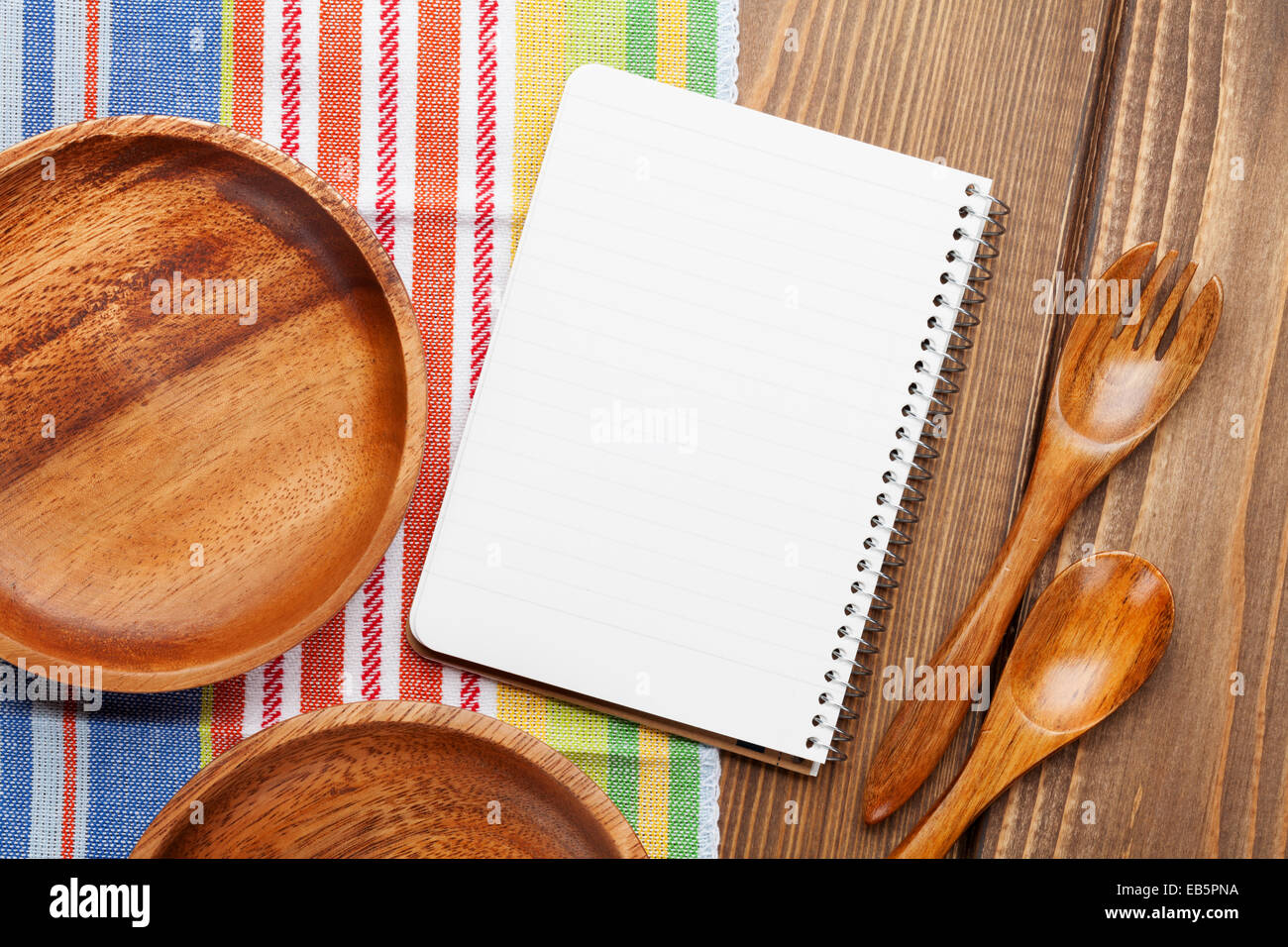 Wood kitchen utensils over wooden table background with notepad for ...