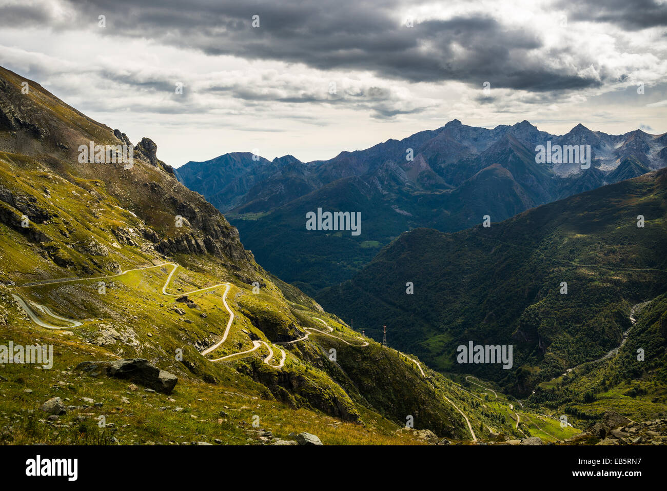 Scenic winding road in alpine valley at sunset with dramatic sky and ...