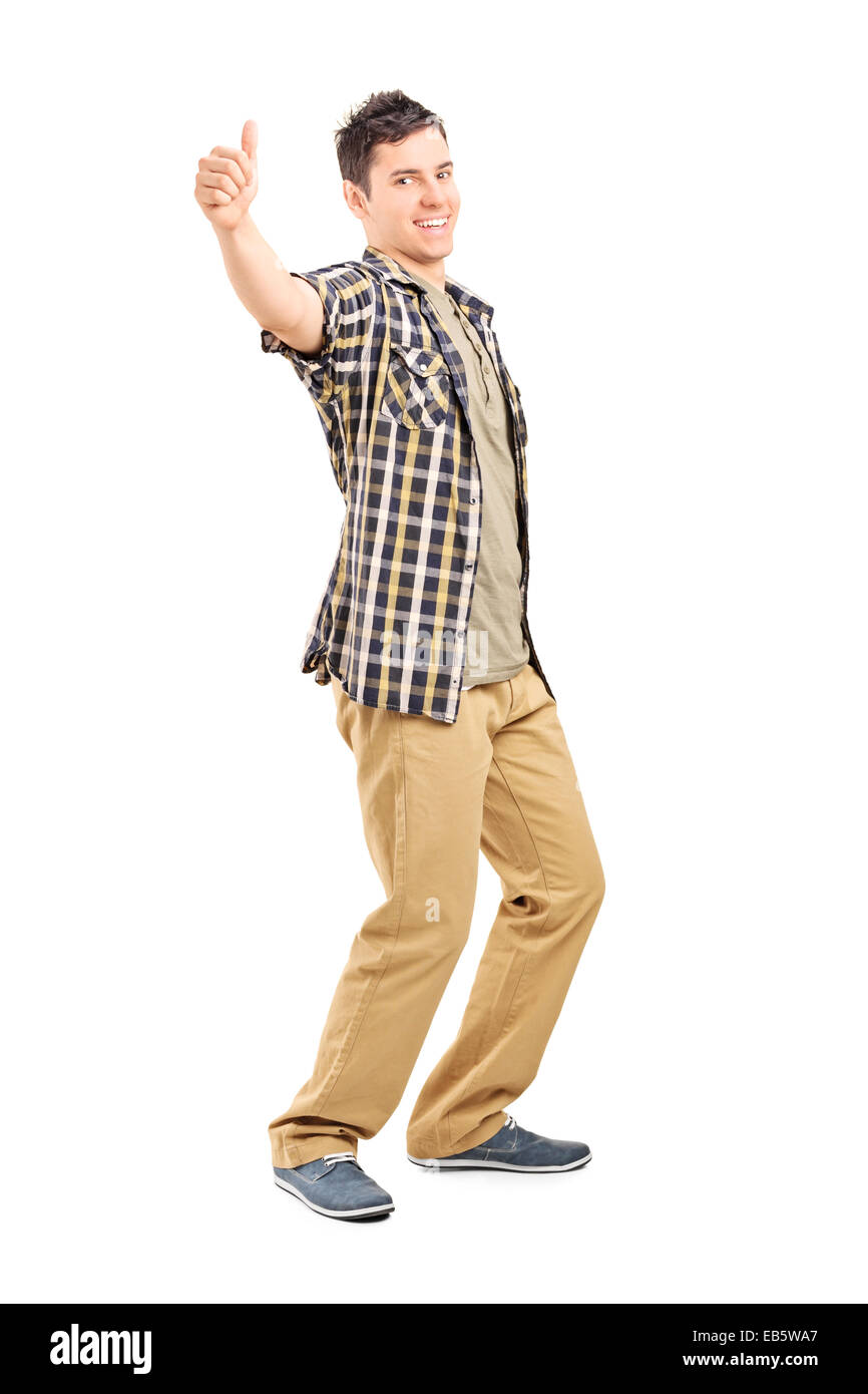 Full length portrait of a relaxed young guy giving a thumb up isolated ...